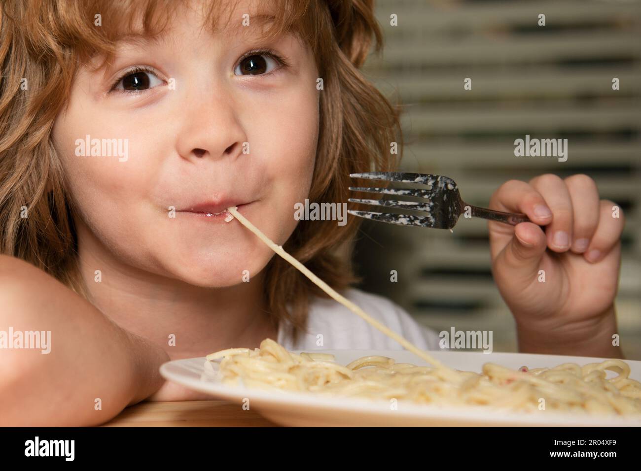 Portrait of a cute child boy eating pasta, spaghetti. Close up ...