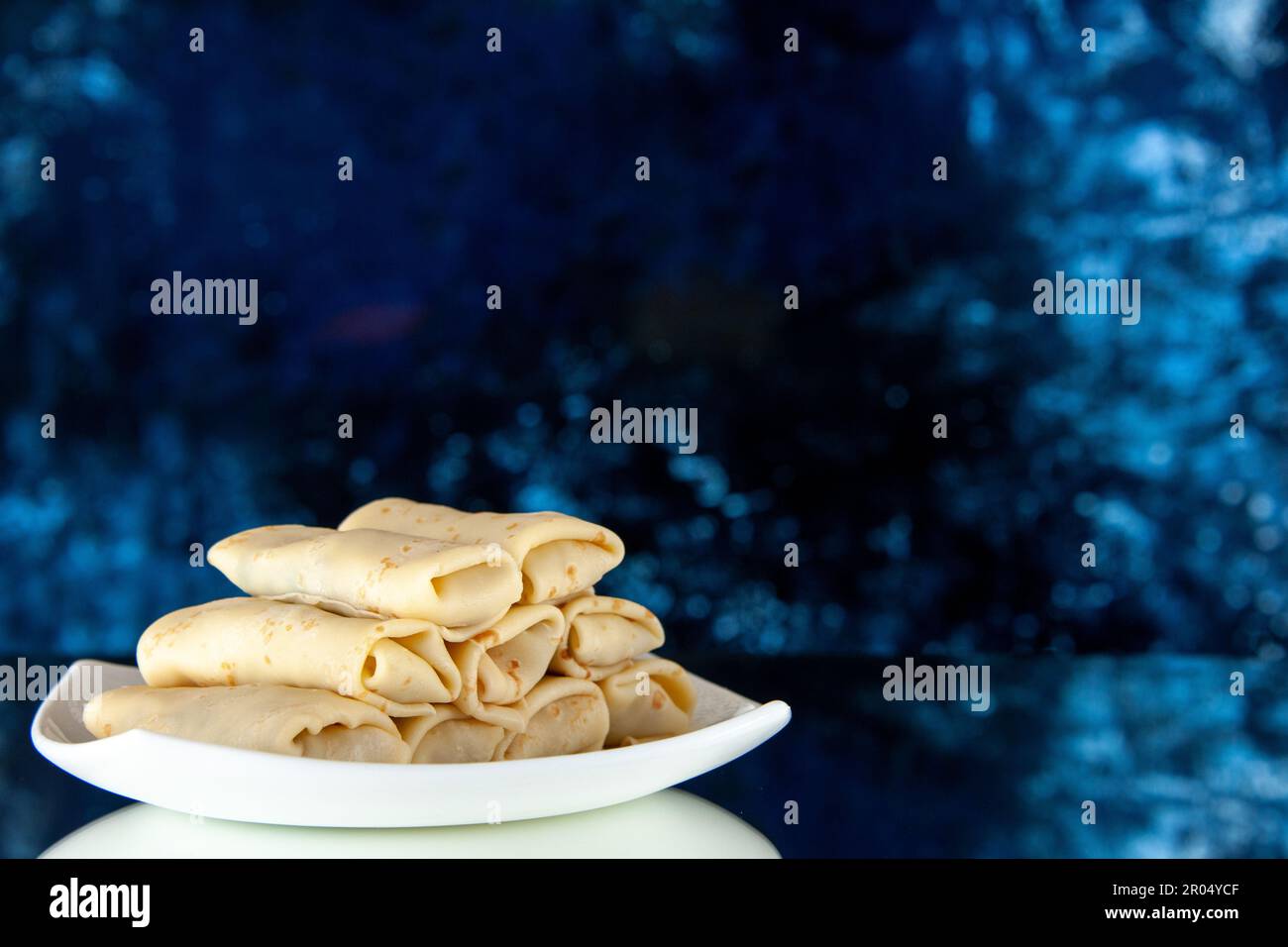 front view delicious sweet pancakes rolled inside plate on dark blue ...
