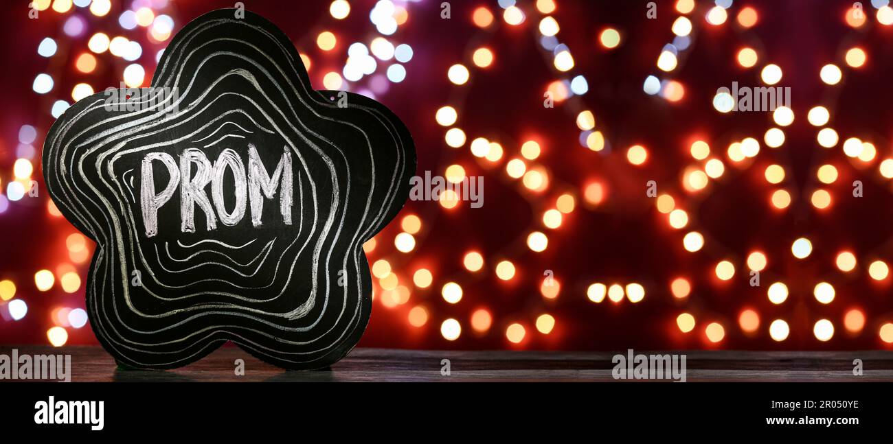 Chalkboard with word PROM on dark background with blurred lights ...