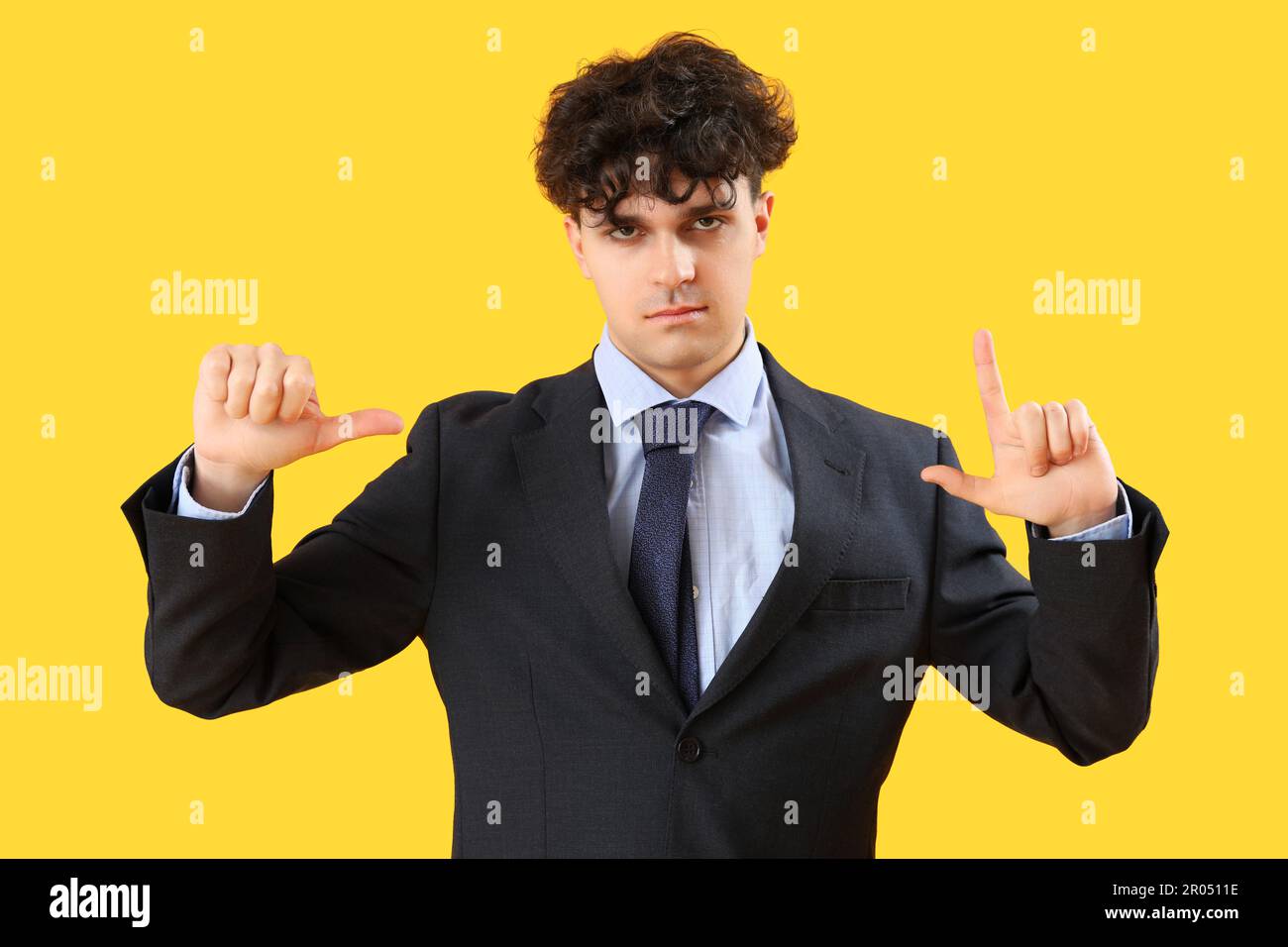Young businessman showing loser gesture on yellow background Stock ...