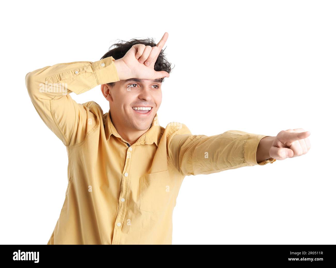Laughing young man showing loser gesture and pointing at something on ...