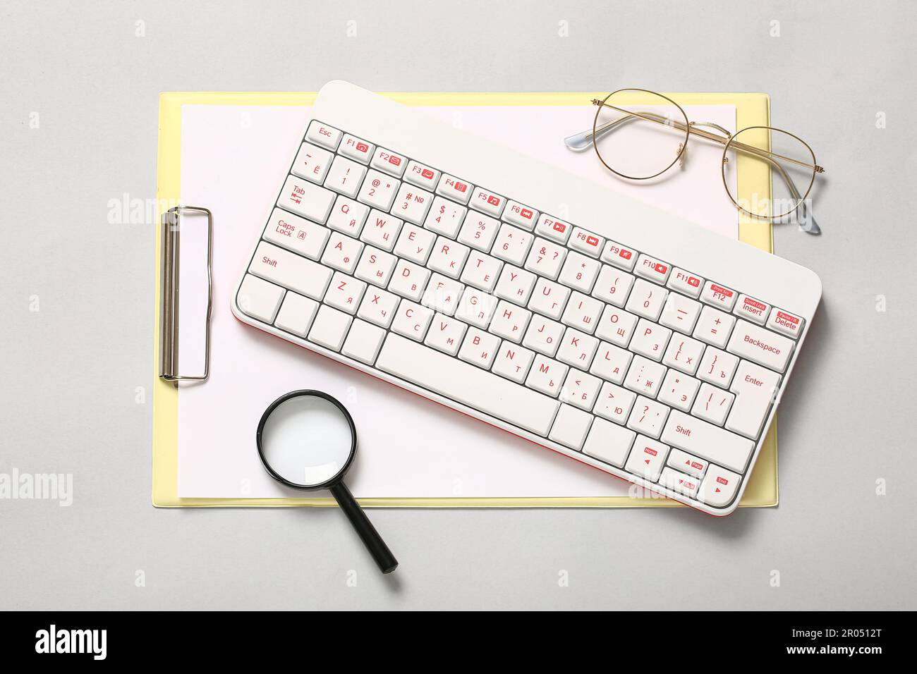 Composition with glasses, keyboard and magnifier on white background ...