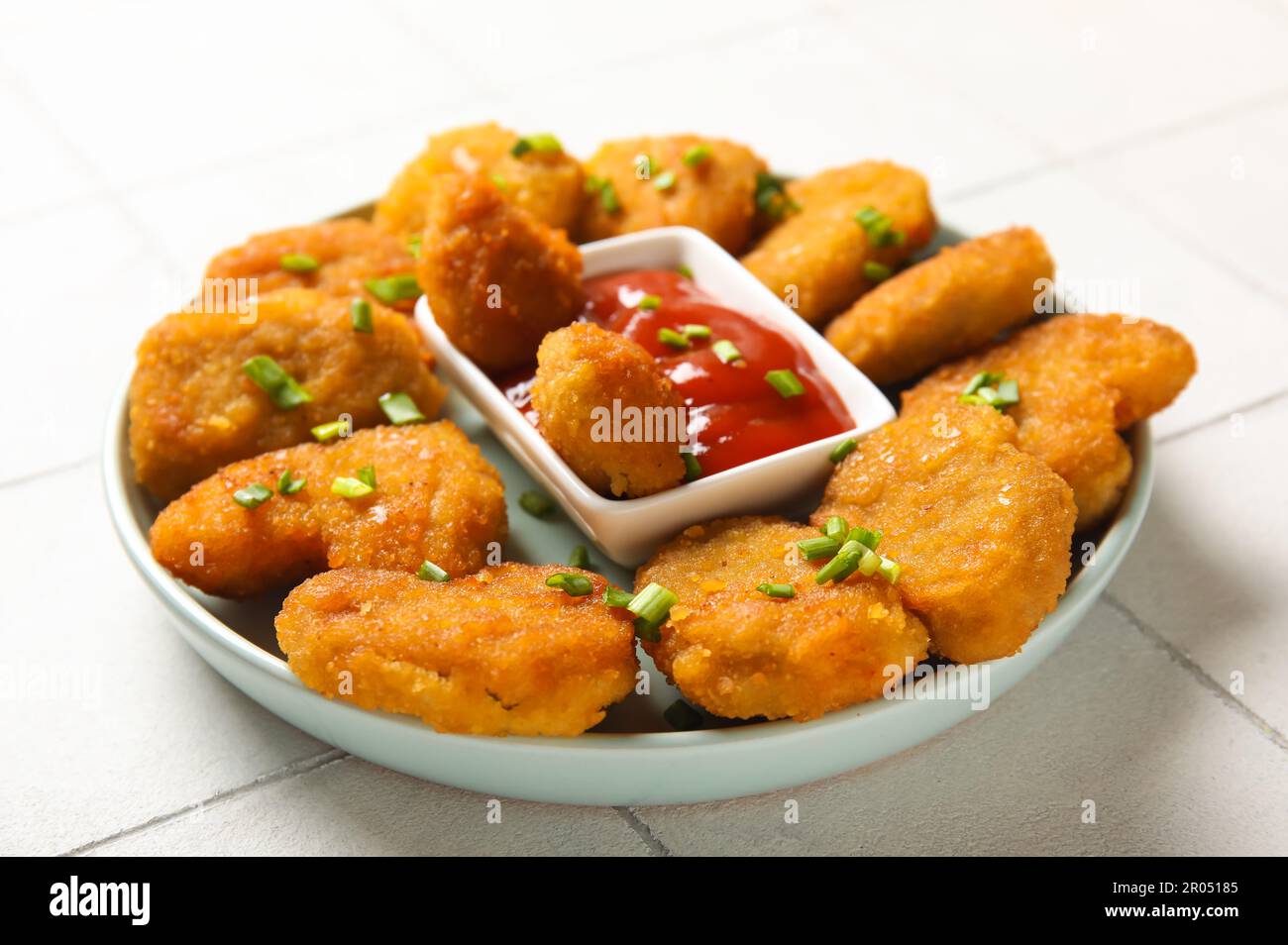 Plate with delicious nuggets, bowl of ketchup and cut green onion on ...