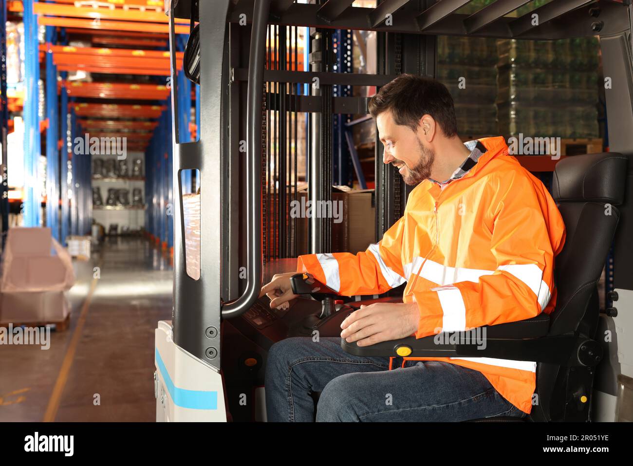 Happy worker sitting in forklift truck at warehouse Stock Photo - Alamy