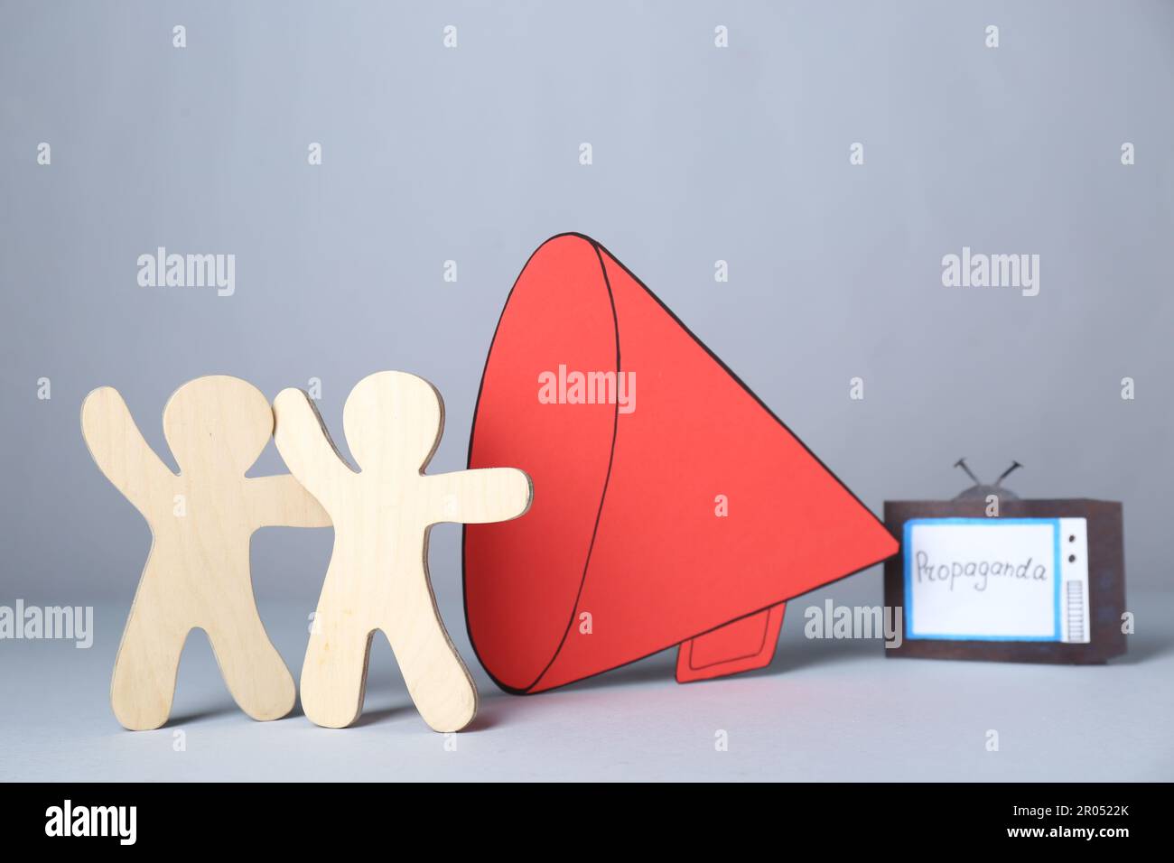 Propaganda concept. Wooden figures near big paper megaphone and TV on ...