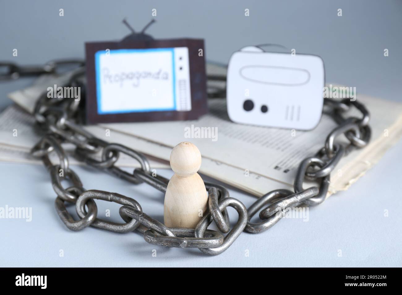 Propaganda concept. Human mired in media field. Chained wooden figure ...