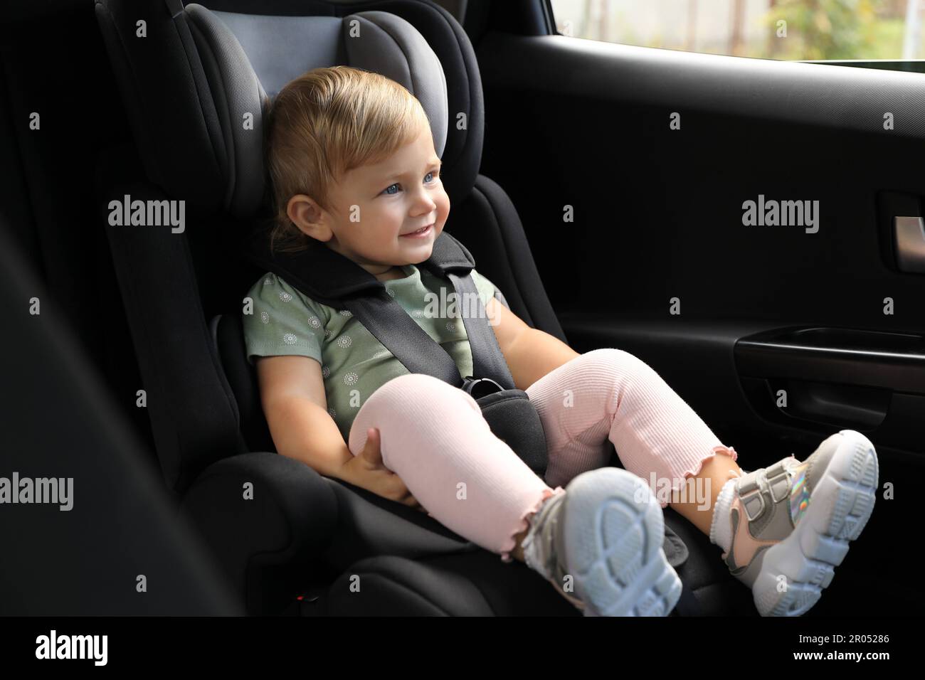 Cute little girl sitting in child safety seat inside car Stock Photo ...