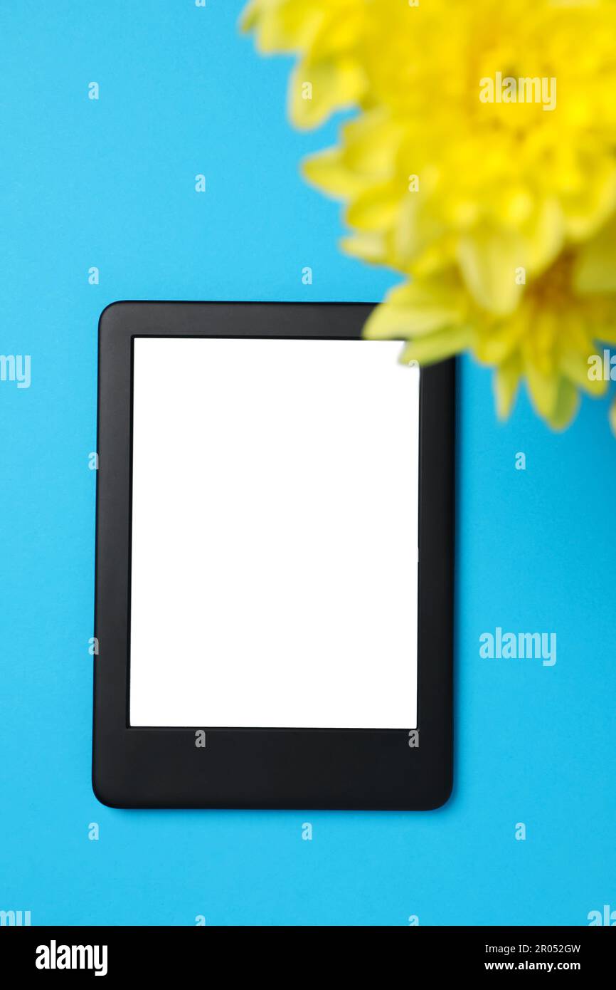 E-book reader with flowers on light blue background, top view. Space ...