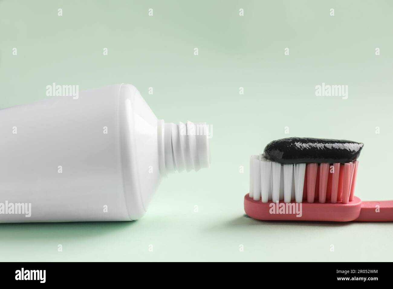 Brush and tube with charcoal toothpaste on white background, closeup ...