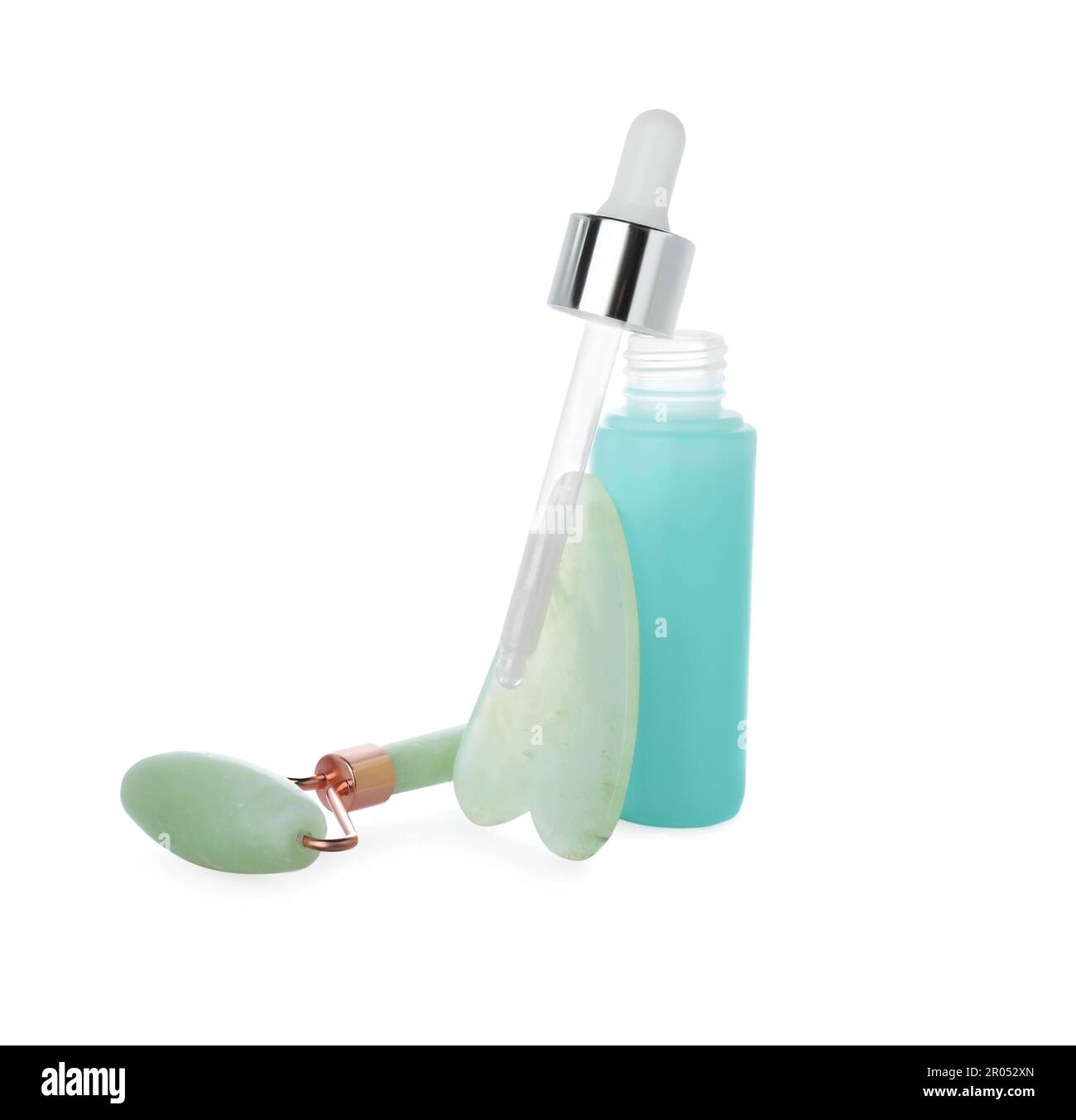 Jade gua sha tool, facial roller and bottle of serum isolated on white ...