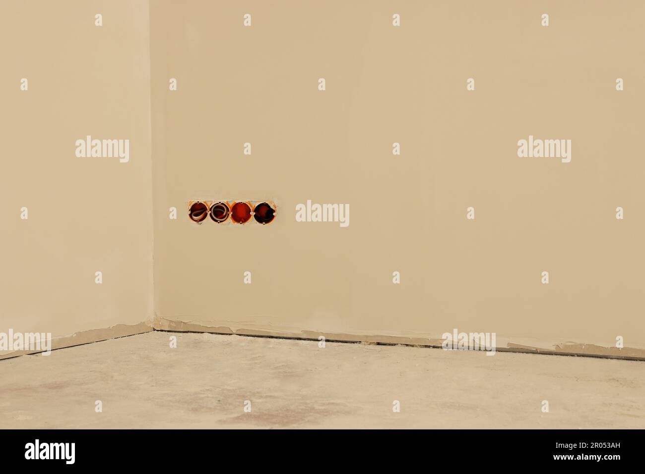 Holes for socket in beige clean wall Stock Photo - Alamy