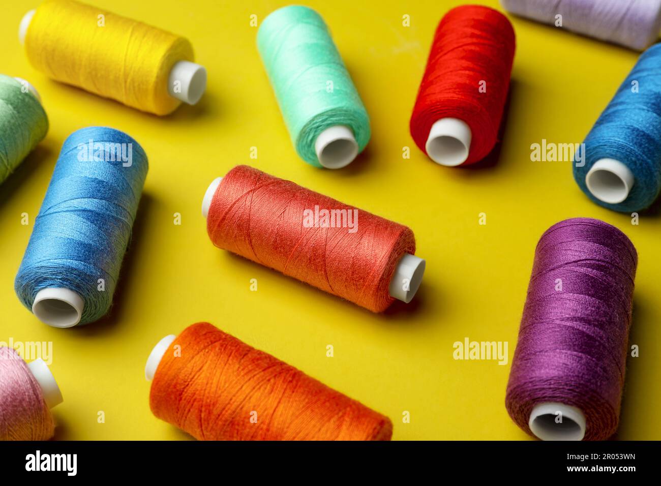 Different colorful sewing threads on yellow background Stock Photo - Alamy