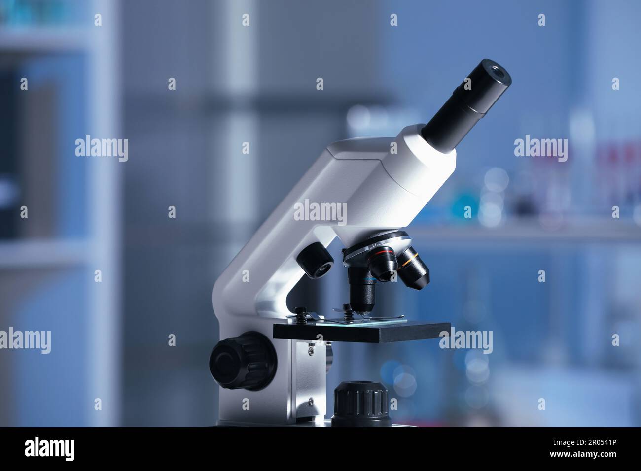 Modern medical microscope with glass slide against blurred background ...