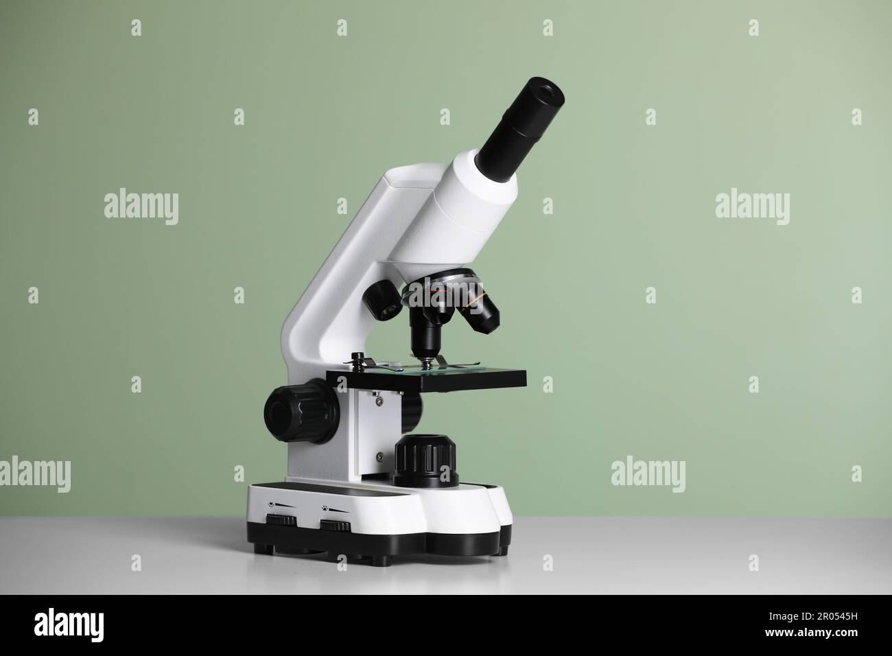 Modern microscope on table against green background Stock Photo - Alamy