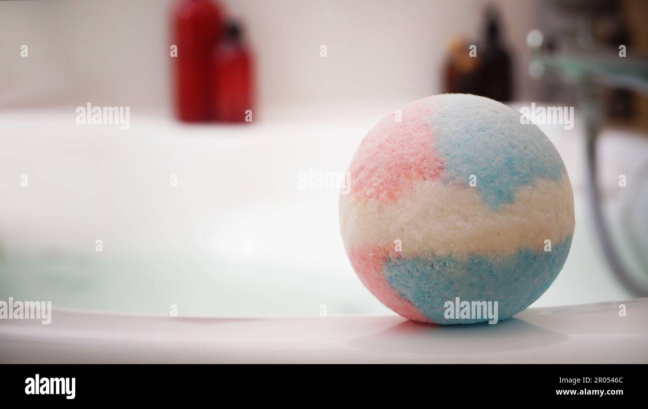 Colorful bath bomb on tub indoors, space for text Stock Photo - Alamy