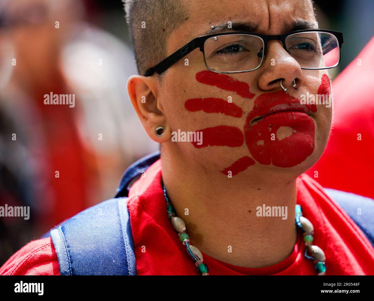 A marcher wears a red handprint on their face during the third annual ...