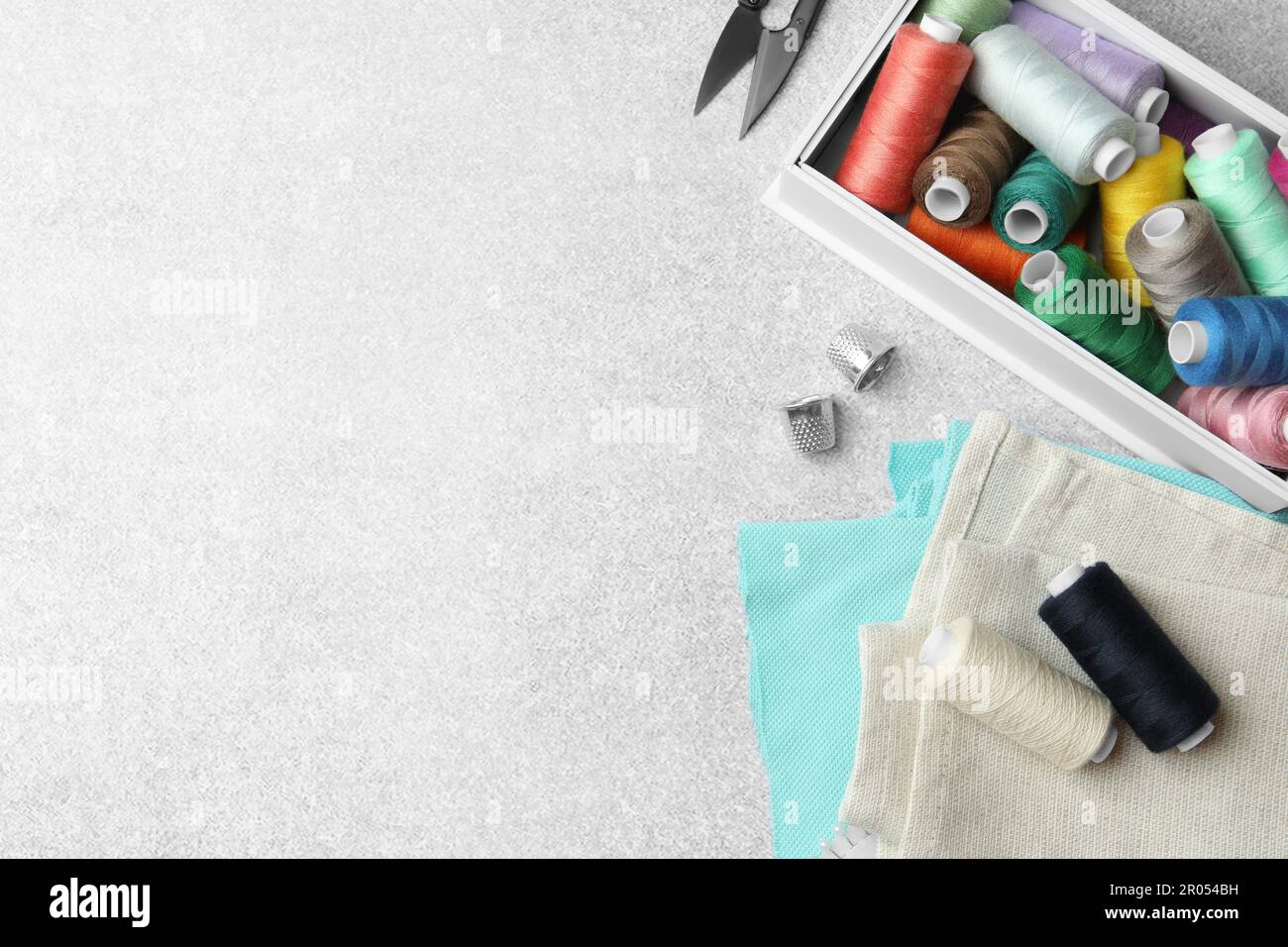 Flat lay composition with spools of threads and sewing tools on light ...