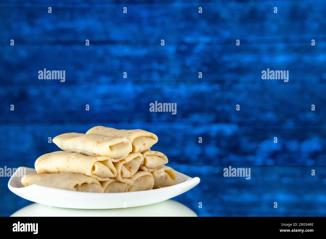 front view rolled sweet pancakes inside plate on dark blue background ...