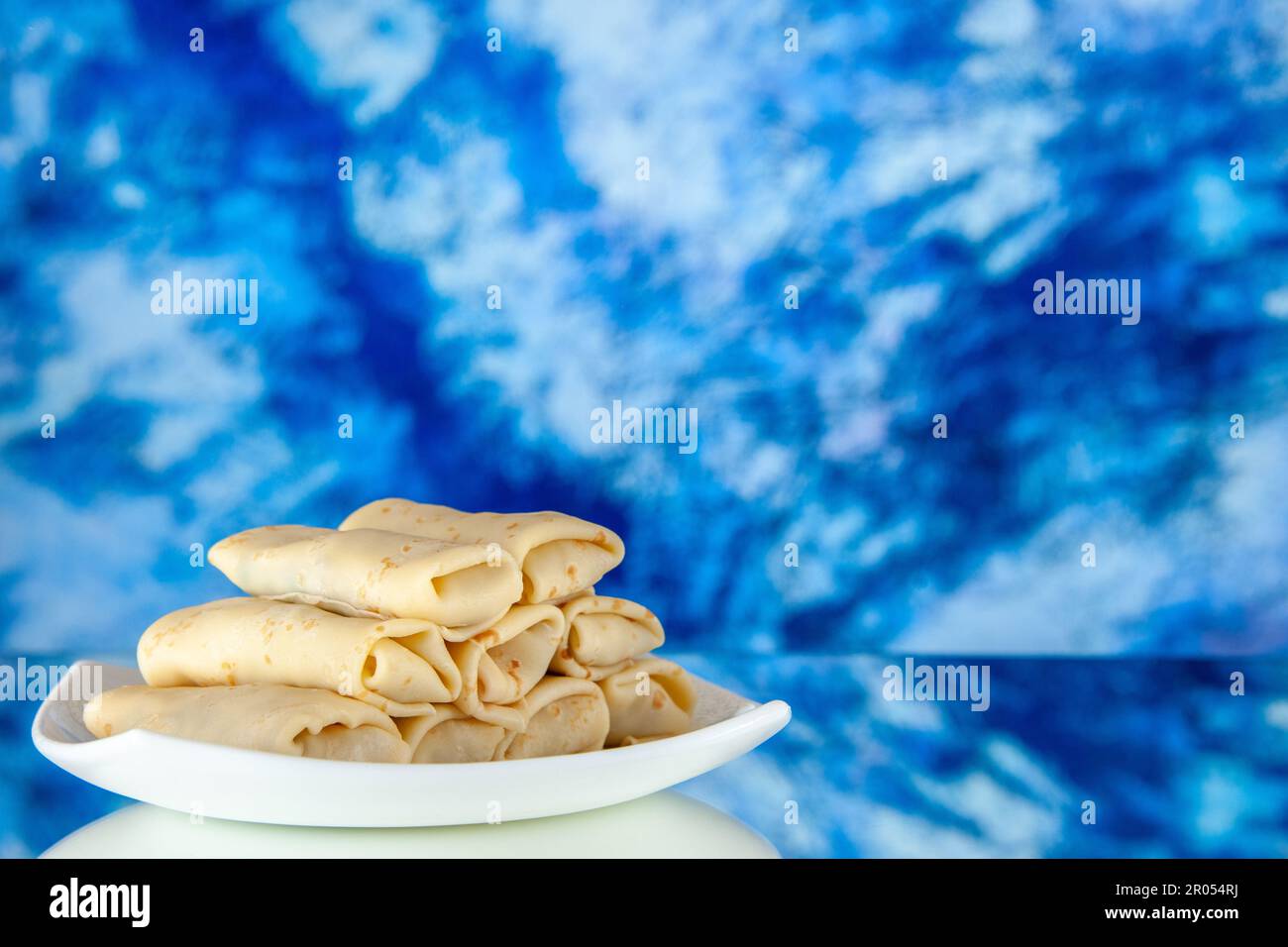 front view rolled sweet pancakes inside plate on light-blue background ...