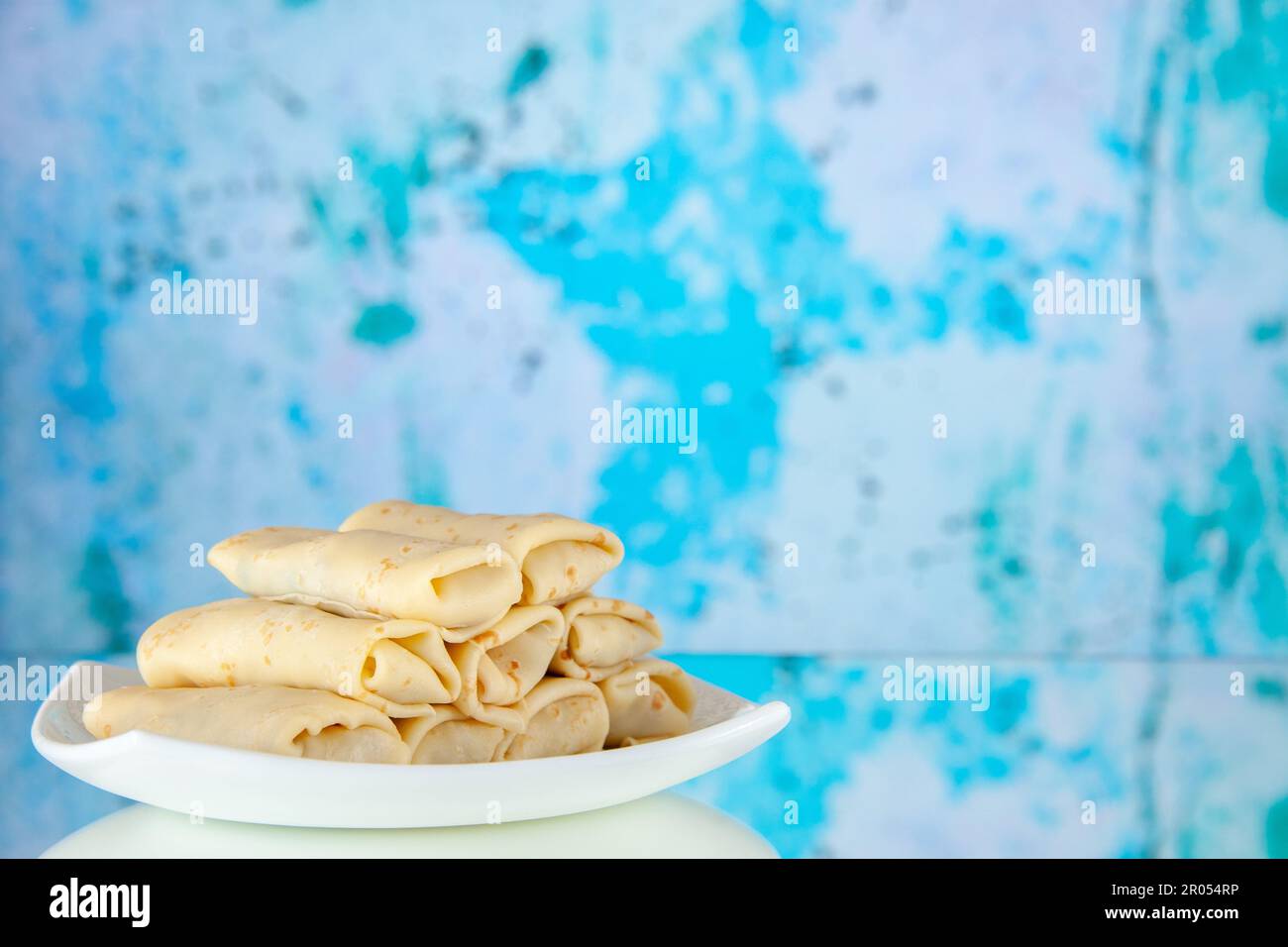 front view rolled sweet pancakes inside plate on light blue background ...