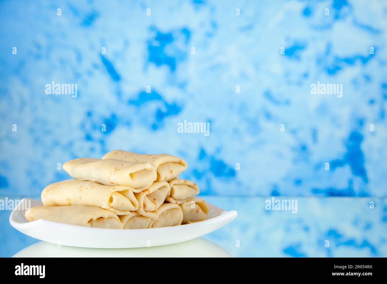 front view rolled sweet pancakes inside plate on light-blue background ...