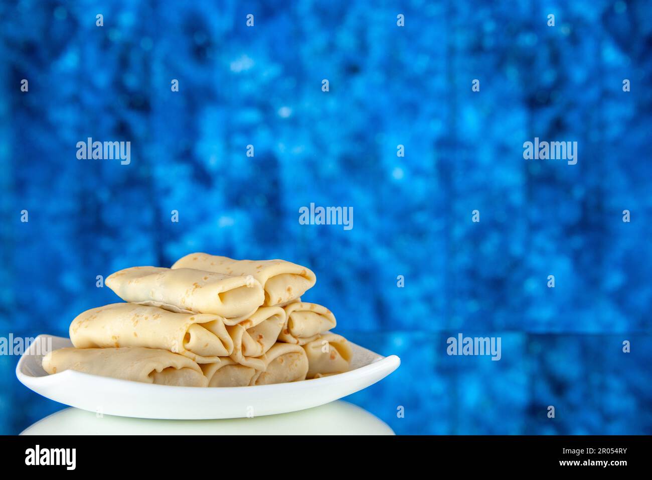 front view rolled sweet pancakes inside plate on light-blue background ...