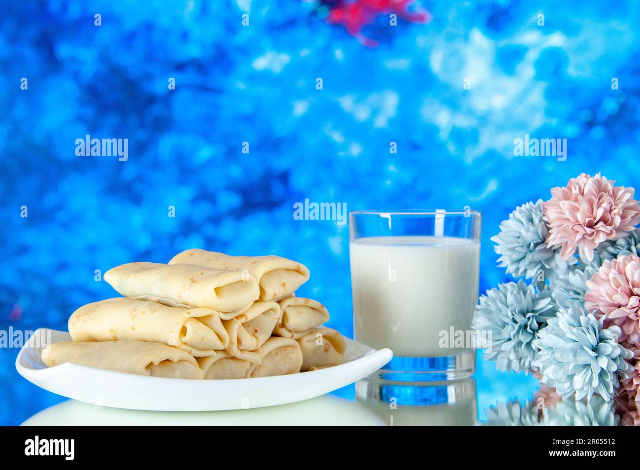 front view rolled sweet pancakes inside plate with glass of milk on a ...