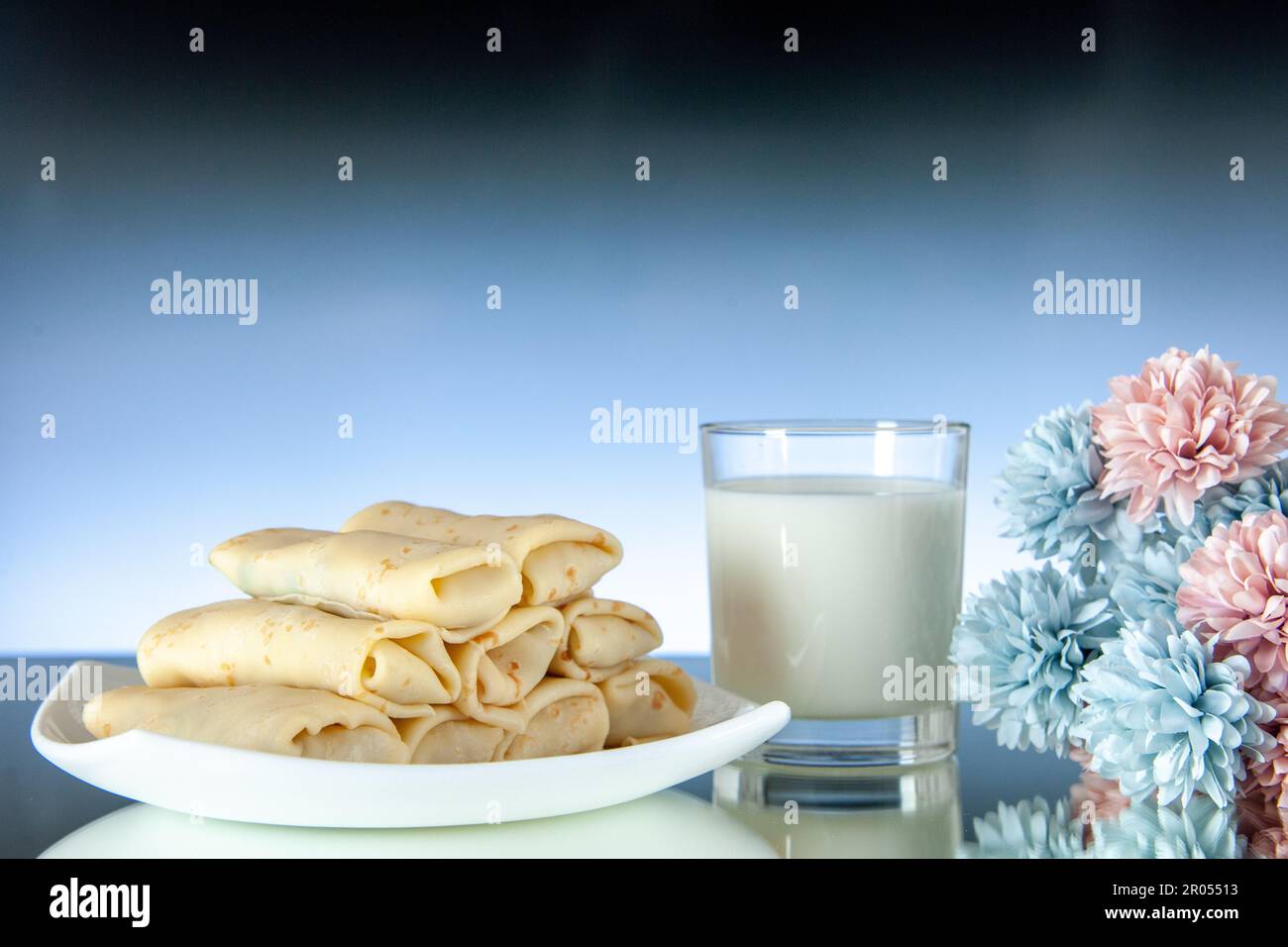 front view rolled sweet pancakes inside plate with glass of milk on ...