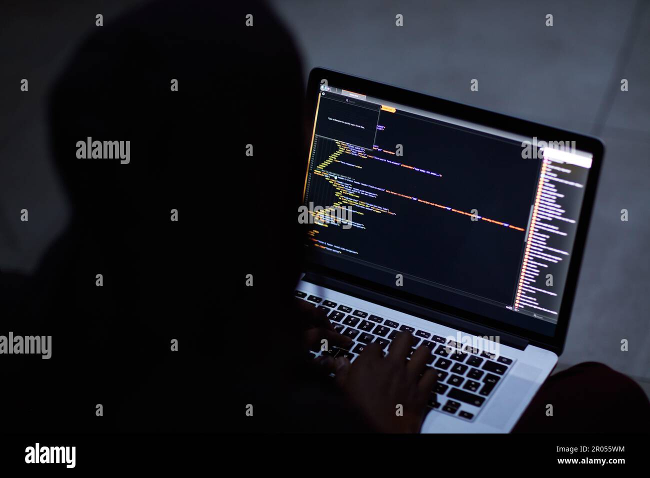 Tapping into the main frame. an unrecognisable hacker using a laptop in the dark Stock Photo - Alamy