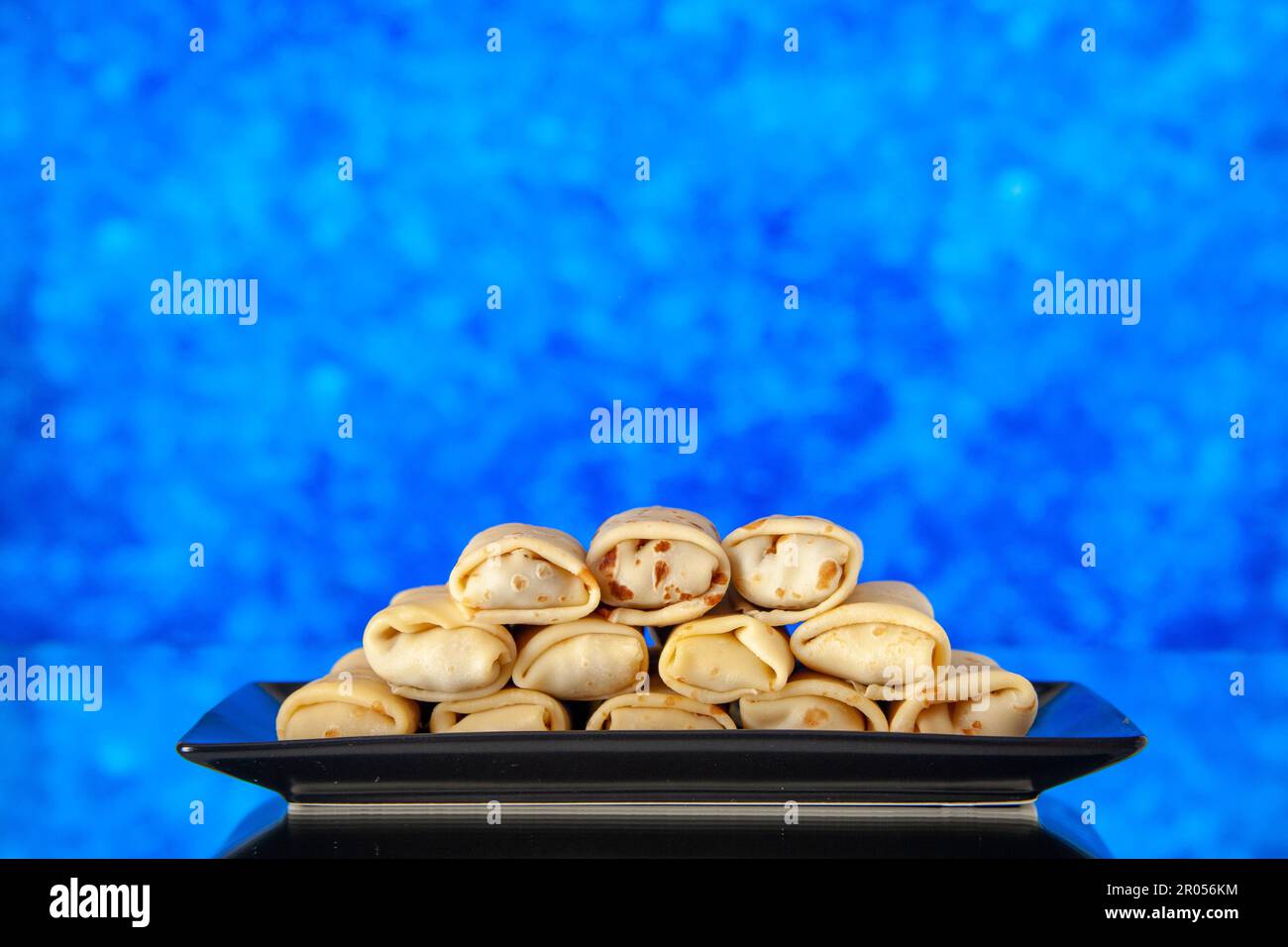 front view yummy rolled pancakes inside plate on a blue background milk ...