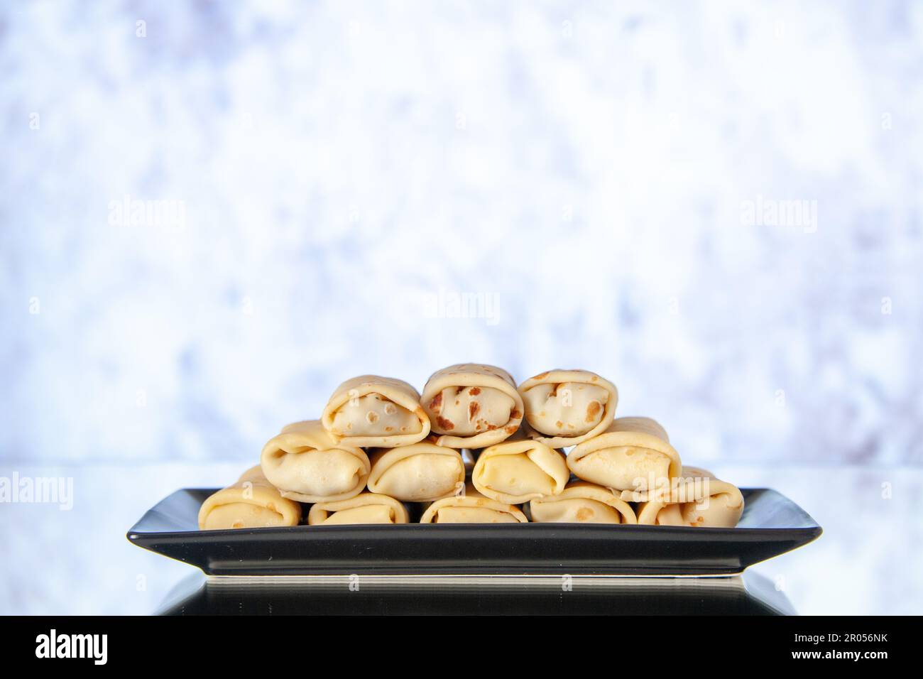 front view yummy rolled pancakes inside plate on a light background ...