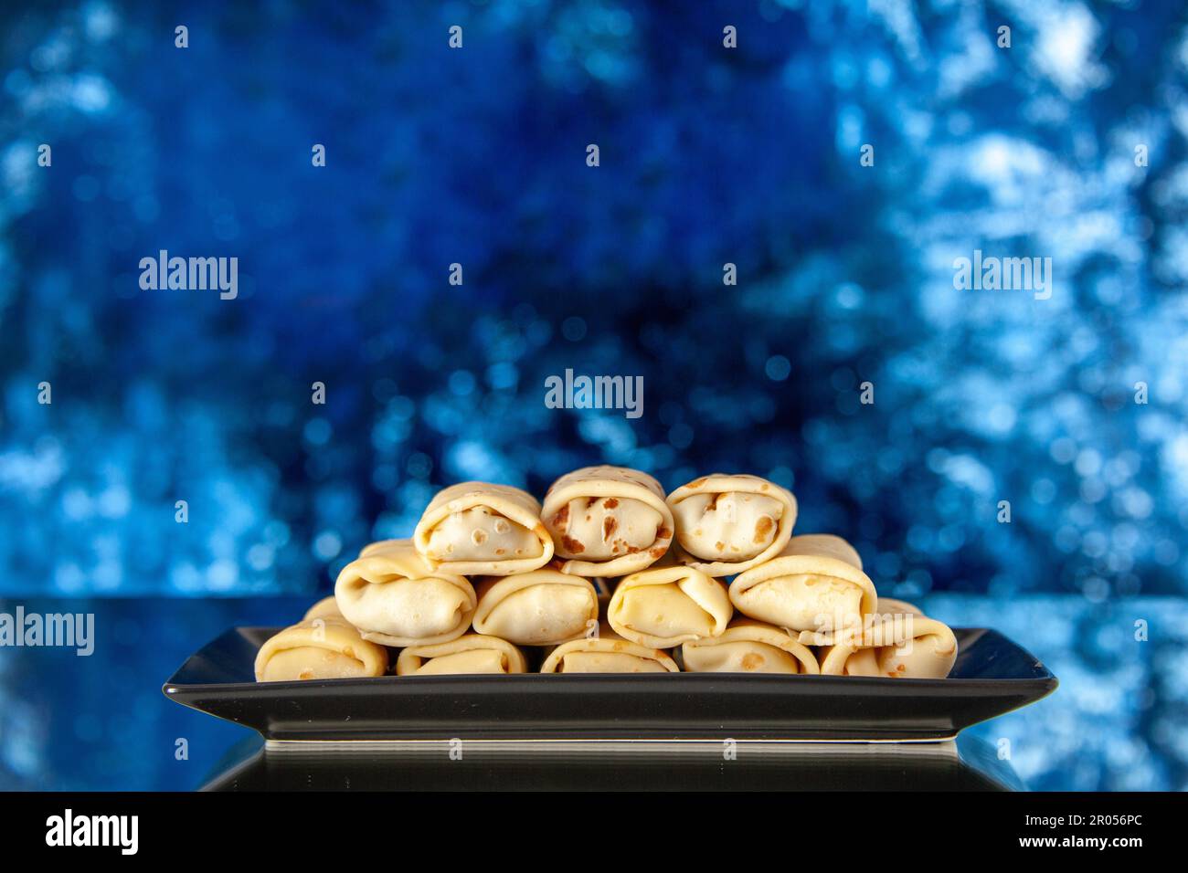 front view yummy rolled pancakes inside plate on blue background sugar ...