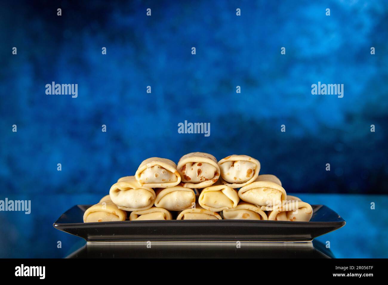 front view yummy rolled pancakes inside plate on dark blue background ...