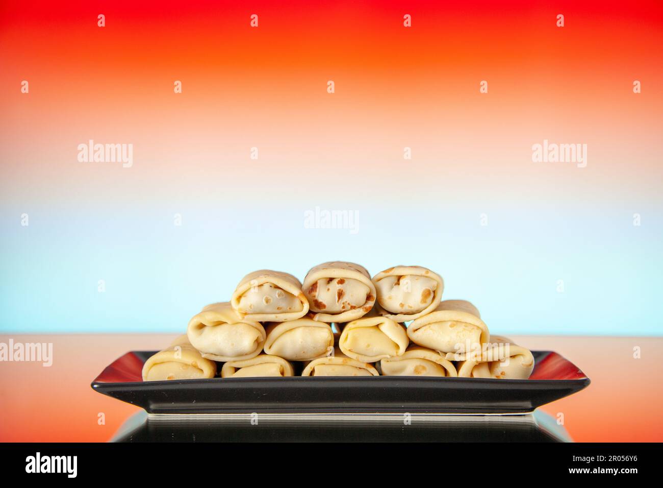 front view yummy rolled pancakes inside plate on light red background ...