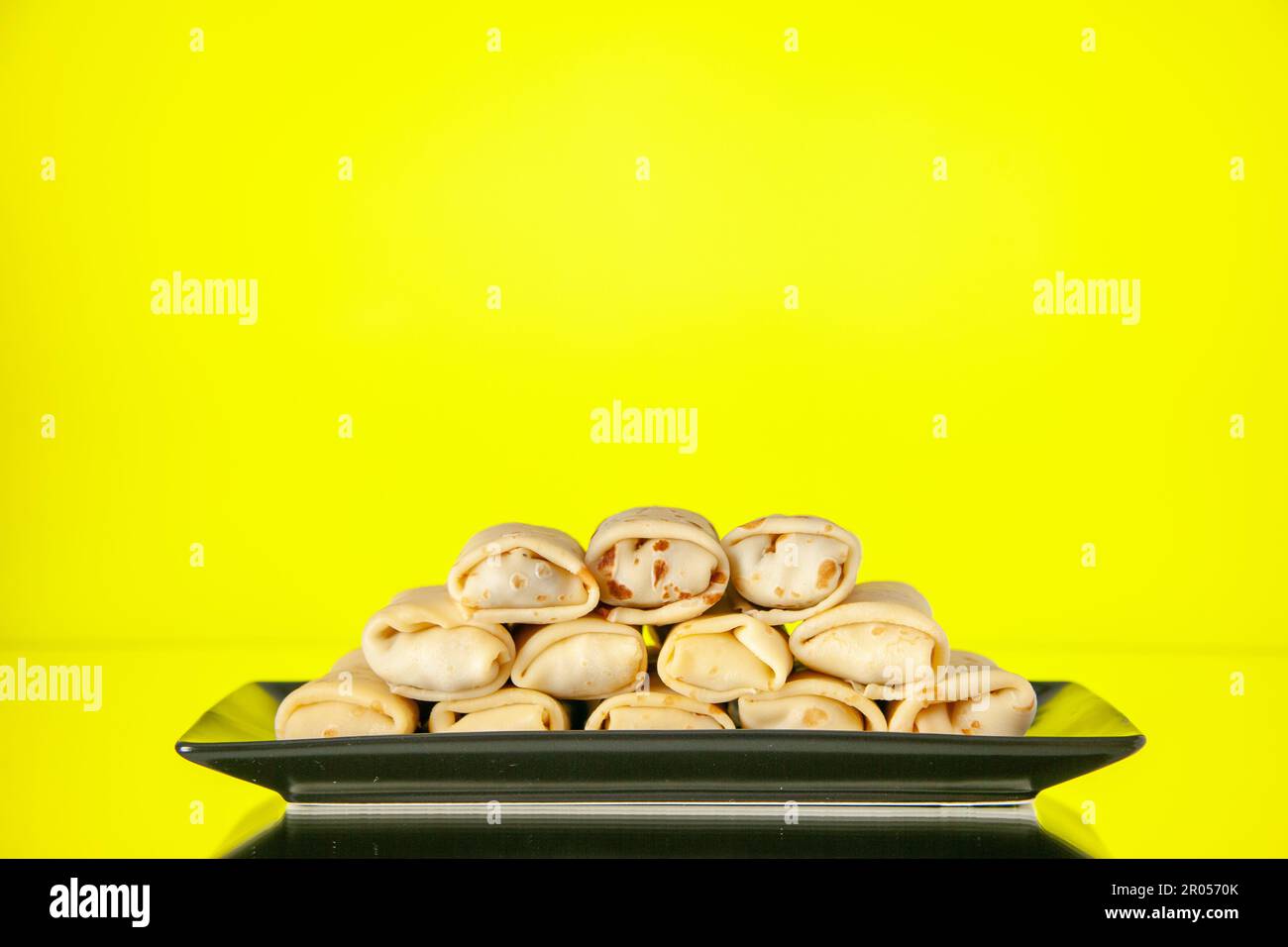 front view yummy rolled pancakes inside plate on yellow background ...