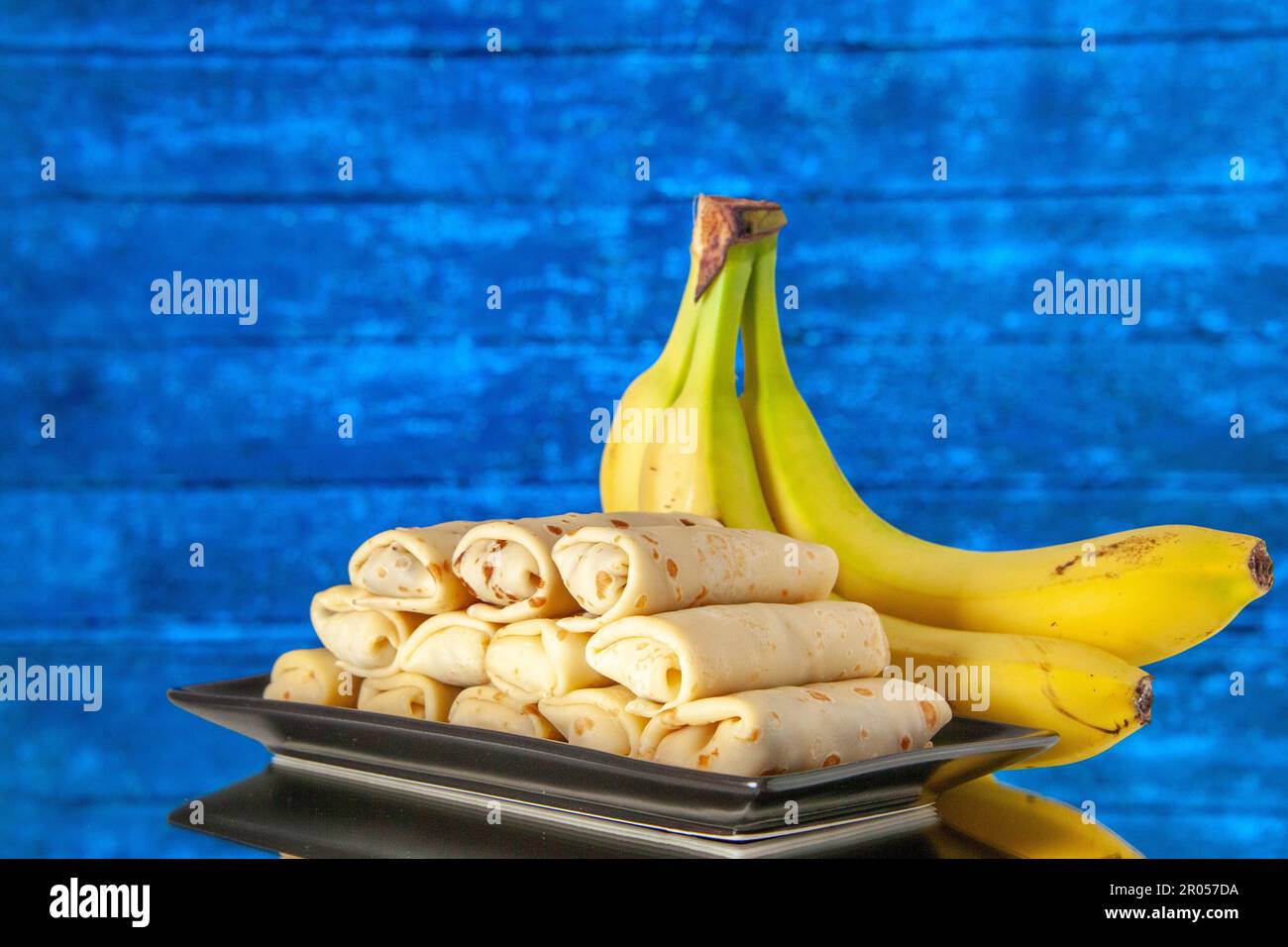 front view yummy rolled pancakes with bananas on a blue background ...