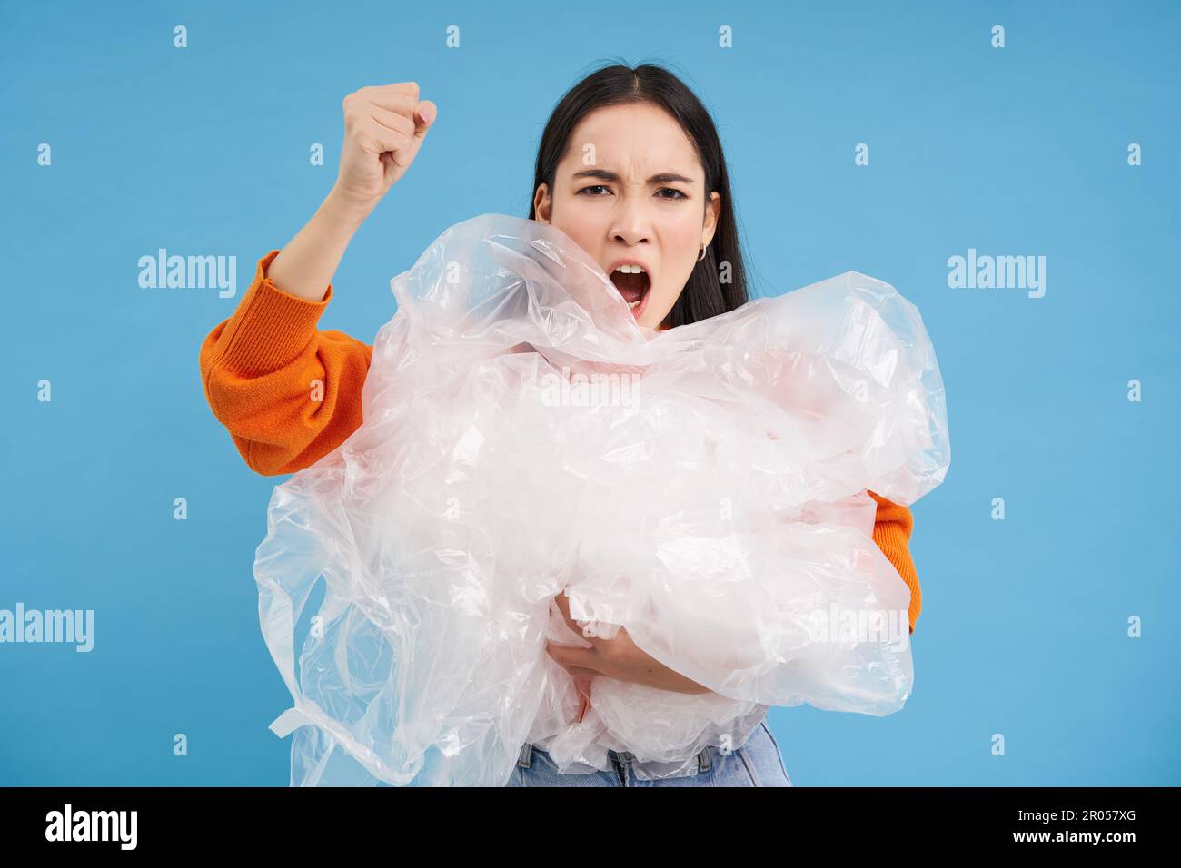 Angry eco-activist holding plastic waste, raising fist and fighting for ...