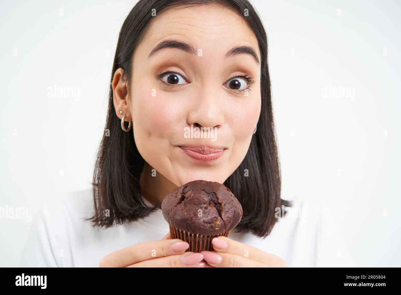 Close up of cute smiling asian woman, holding chocolate cupcake near ...