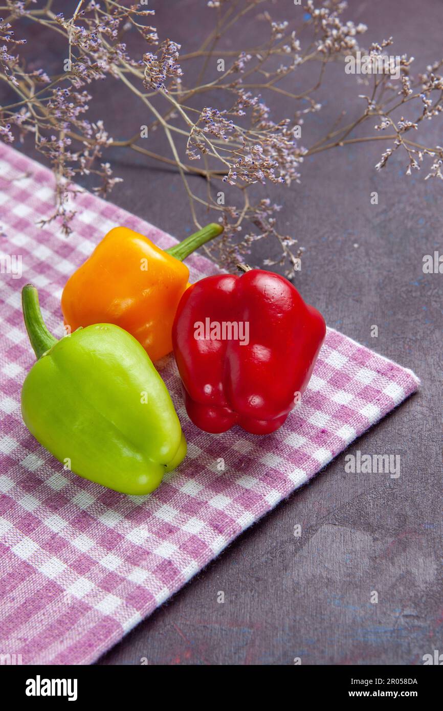 front view colored bell-peppers fresh ones on a grey background ...