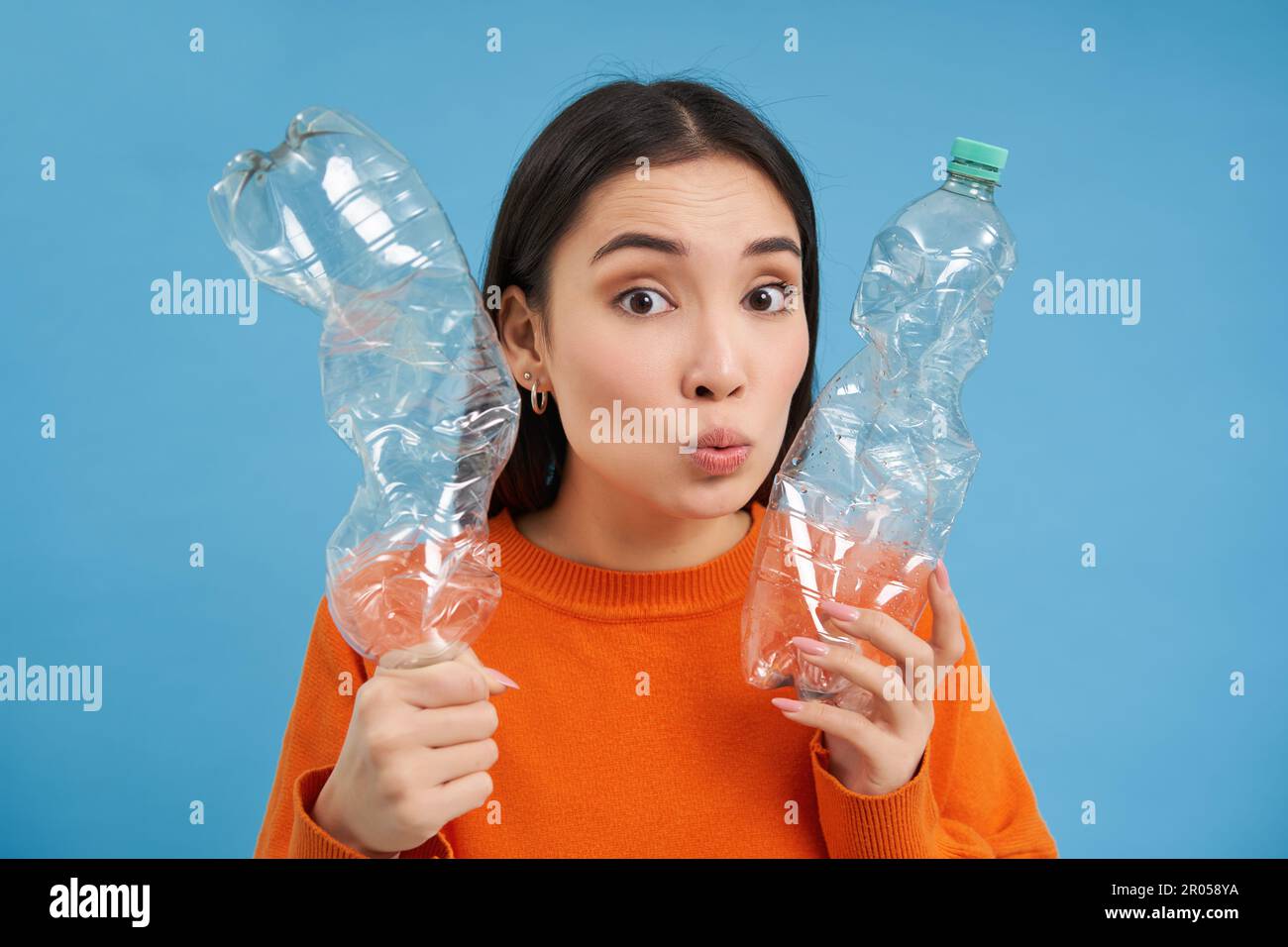 Portrait of cute korean woman, holding two plastic bottles with excited ...