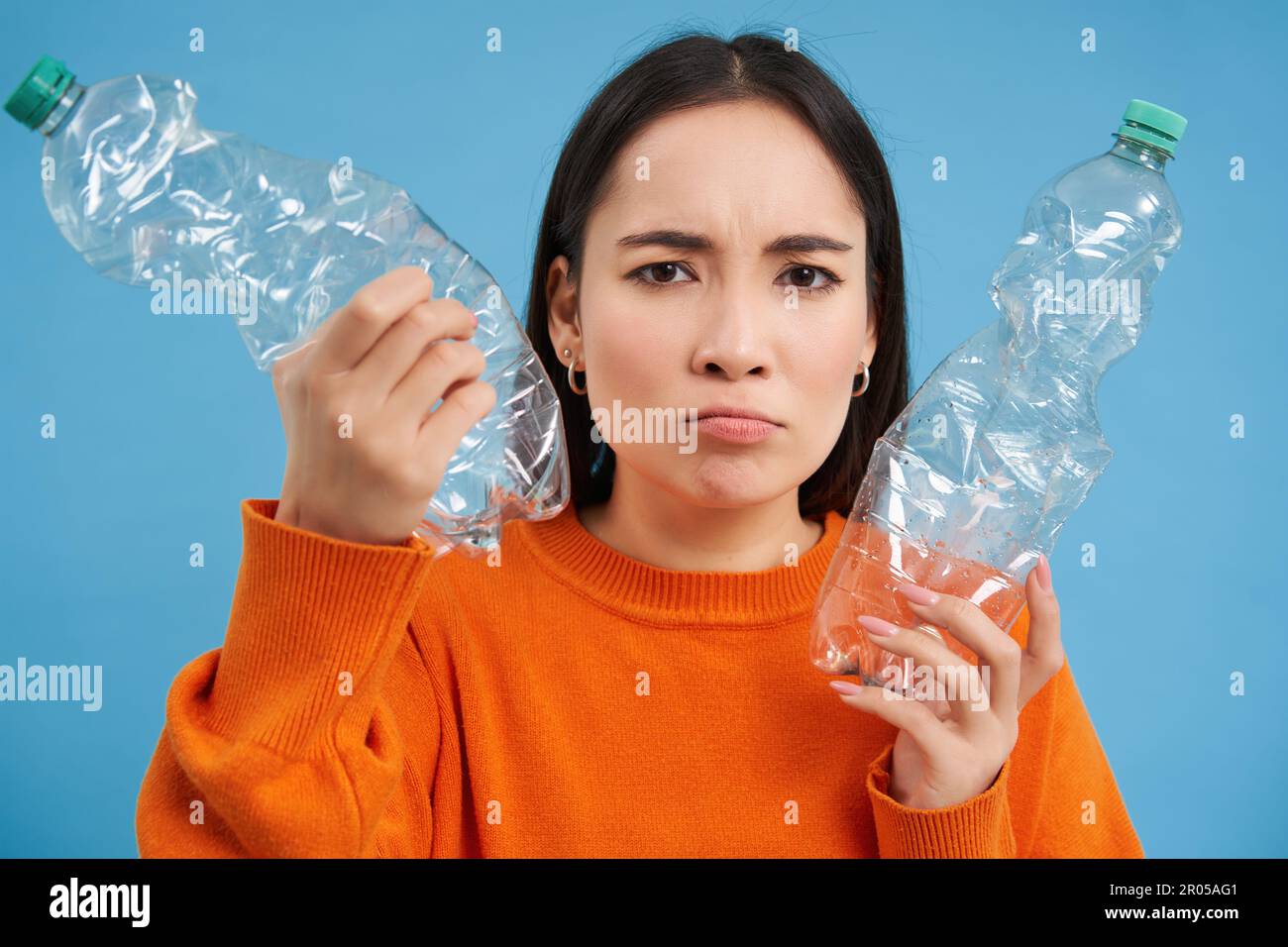 Portrait of sad asian woman with plastic bottles, upset by lack of ...