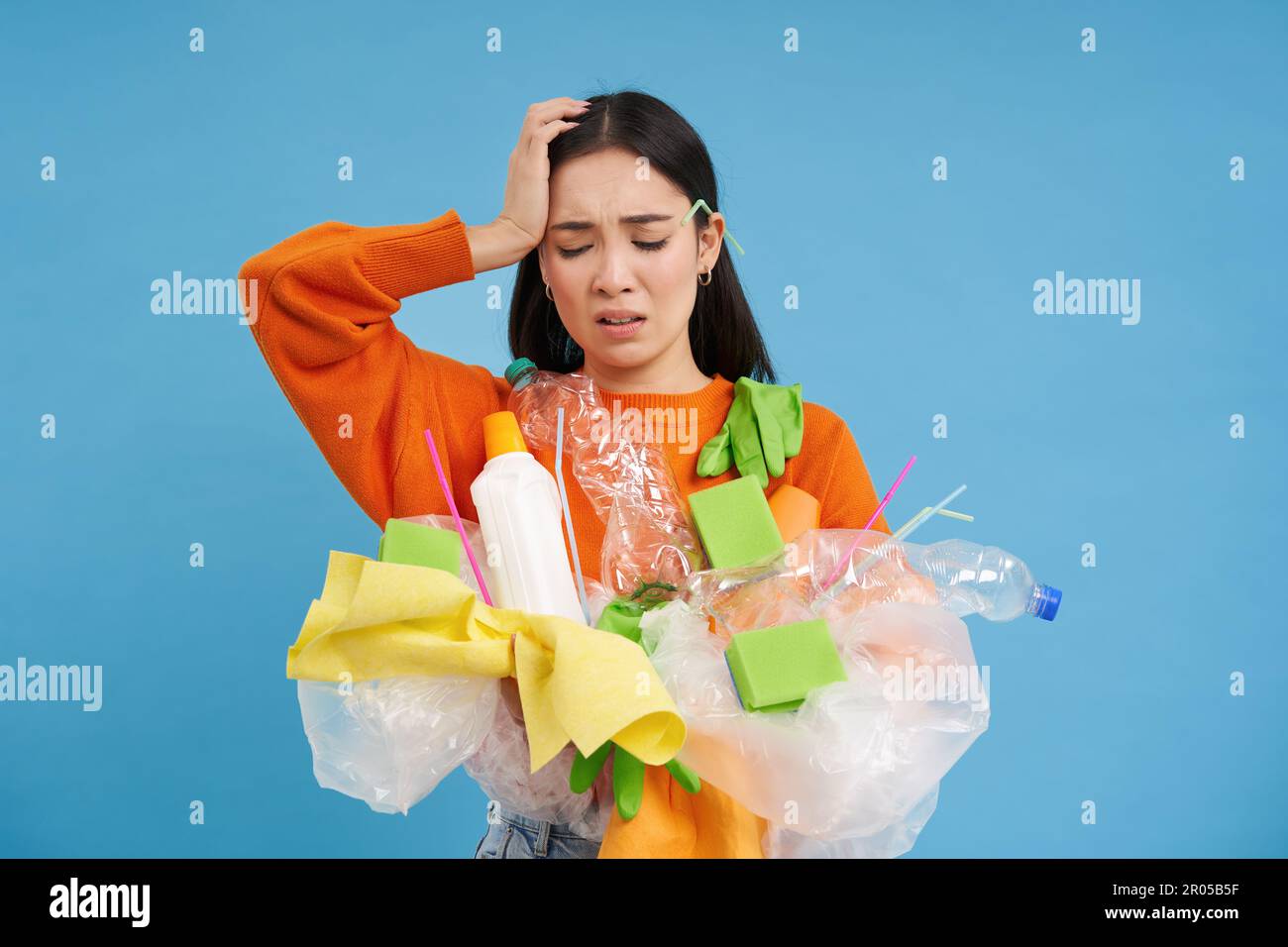 Woman with complicated face, looking confused at plastic garbage ...