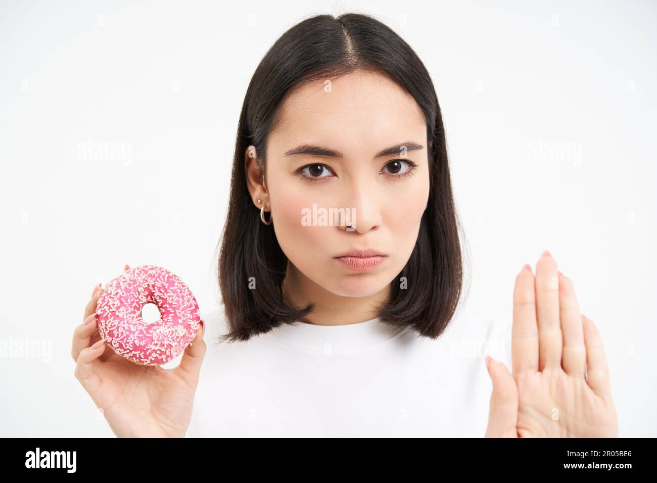 No sweets. Serious young woman on diet, showing stop gesture and glazed ...