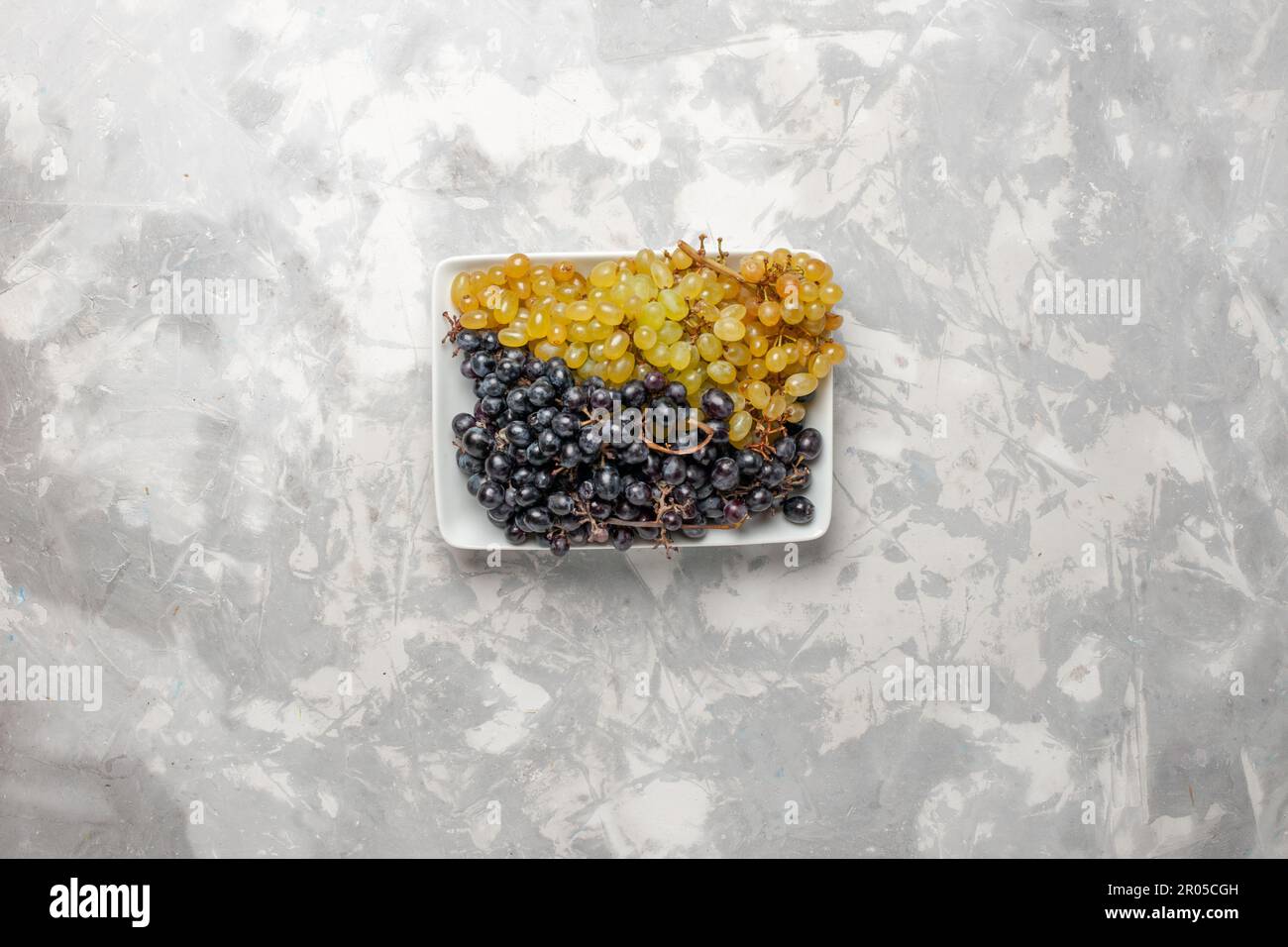 top view fresh grapes mellow and juicy fruits inside plate on white ...