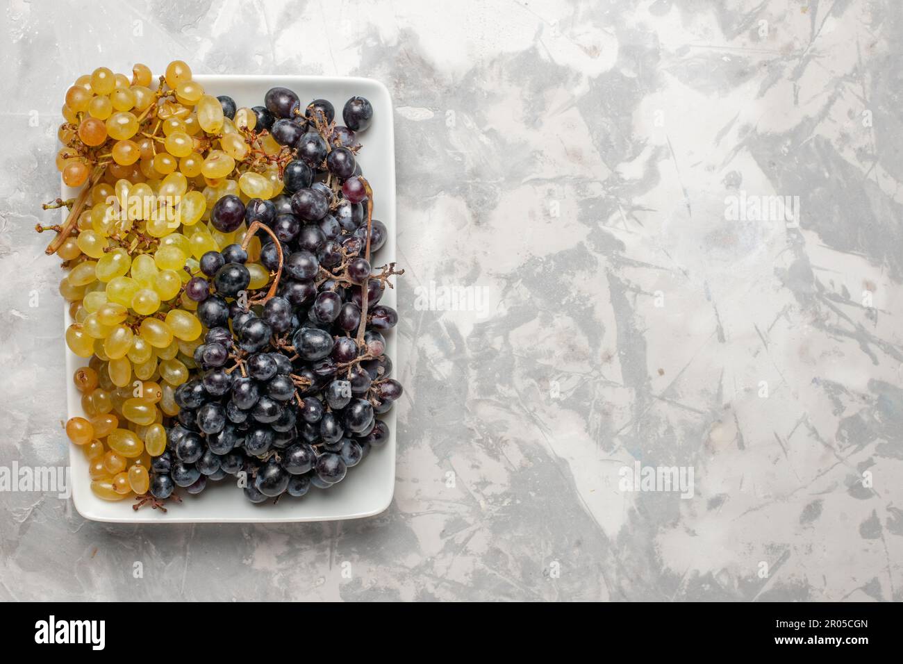 top view fresh grapes mellow and juicy fruits inside plate on a white ...