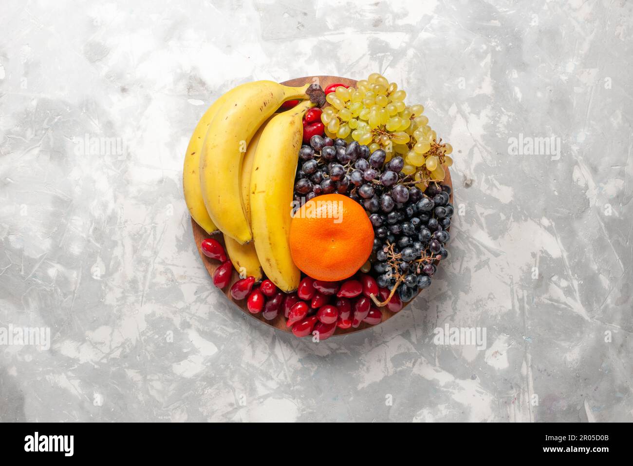 top view fruit composition fresh bananas dogwoods and grapes on white ...