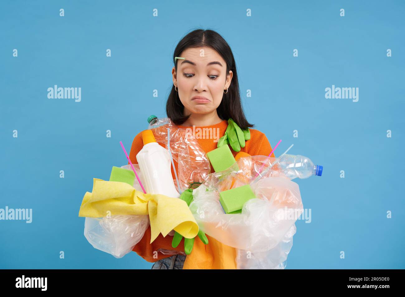 Confused asian woman holds plastic waste, collects garbage to recycle ...