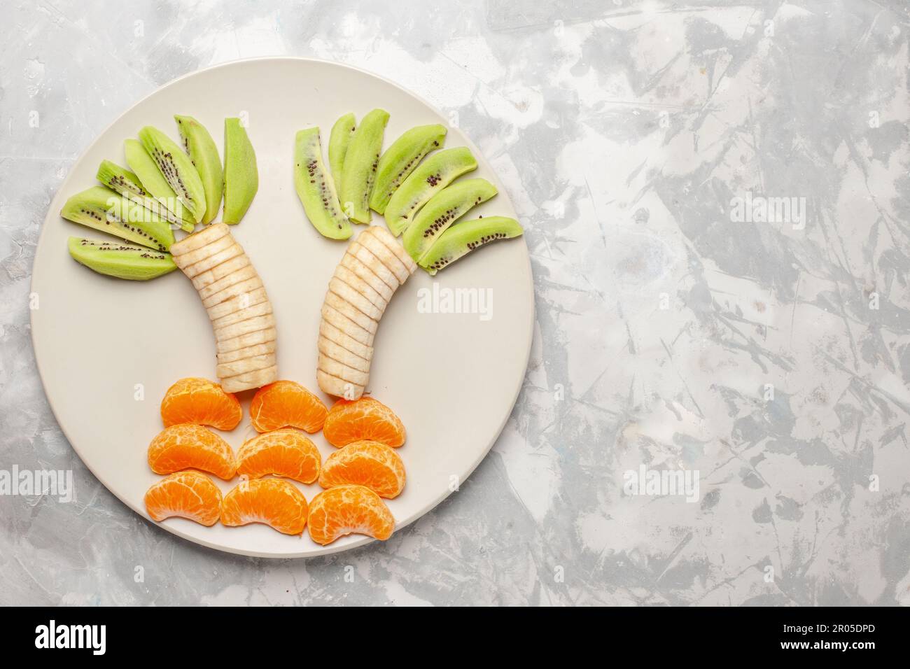 top view sliced fruits kiwis bananas and tangerines on white background ...
