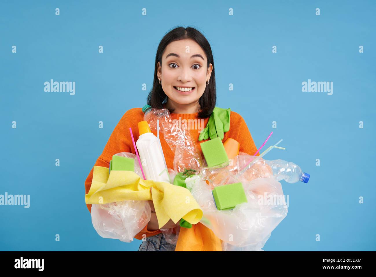 Happy girl looks at plastic garbage, sorting her waste for recycling ...