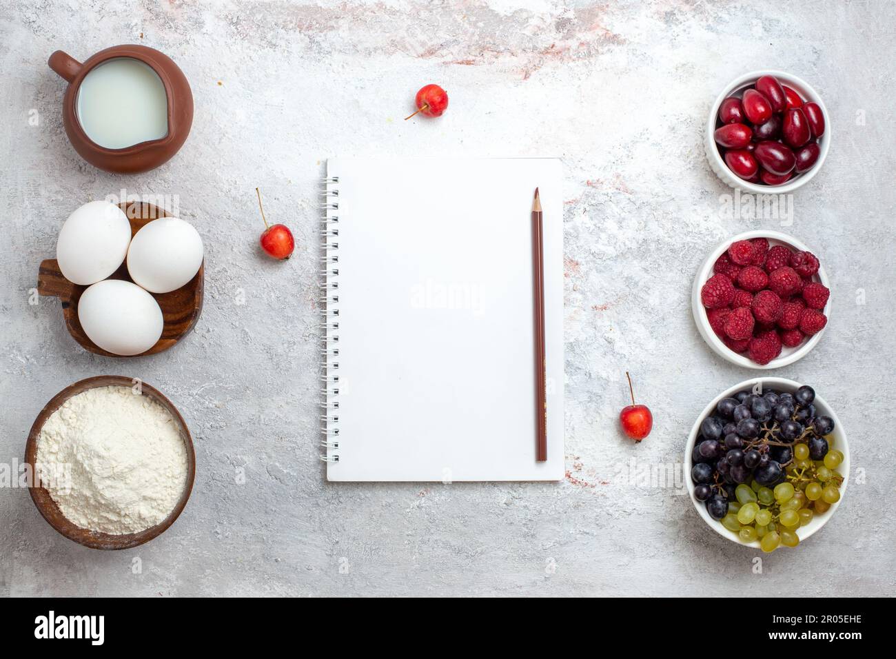 top view whole raw eggs with flour fruits and milk on the white ...